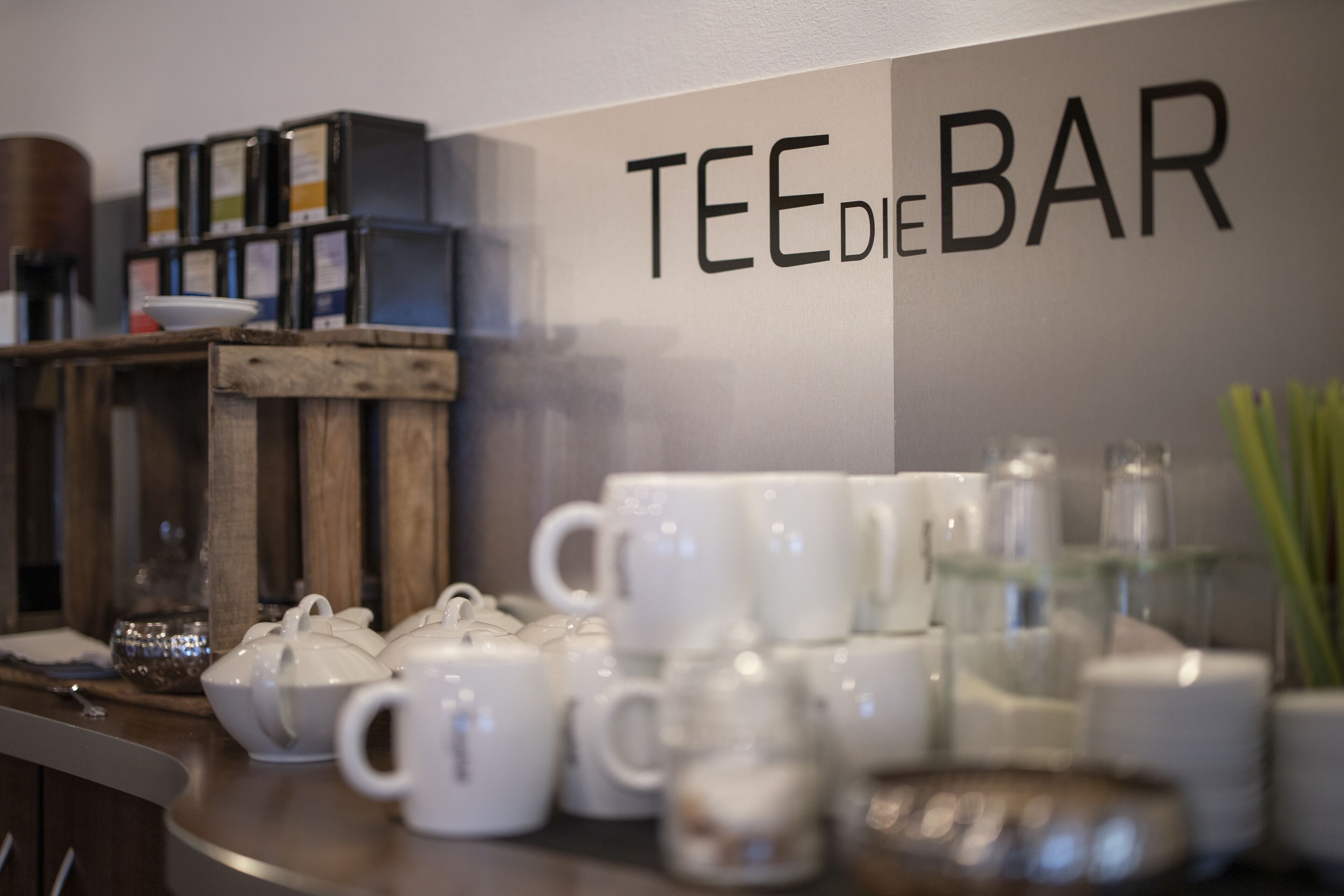Uma área de bar com uma placa que diz 'TEE DE BAR' e uma exibição de canecas e bules brancos.