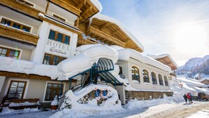 Um hotel com arquitetura alpina tradicional, com varandas de madeira e fachada coberta de neve.