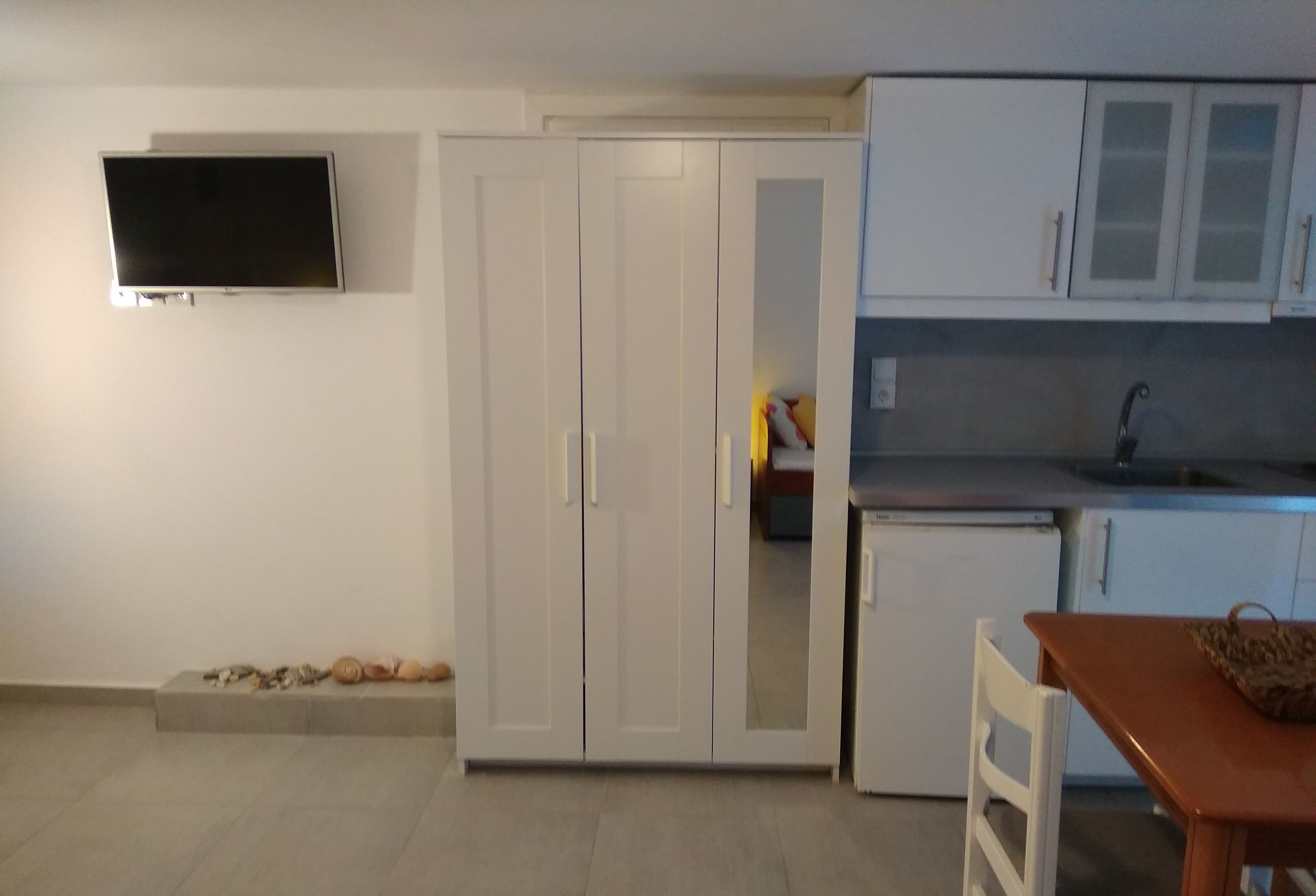 Uma cozinha compacta com forno embutido, um refrigerador pequeno e uma área de refeições com mesa e cadeiras.