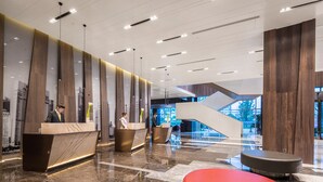 Um hall moderno com balcão de recepção, escada e área de estar vermelha.