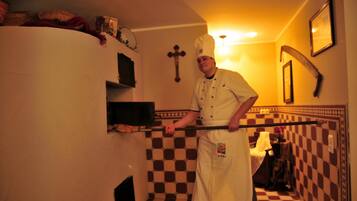 Um chef em uma cozinha com paredes de azulejos xadrez e uma cruz na parede.