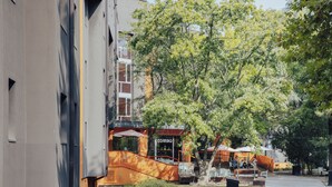 Uma área externa com mesas e cadeiras, uma escadaria e um edifício com um letreiro 'COMBO'.