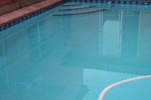 Piscina com borda azulejada e escada visível.