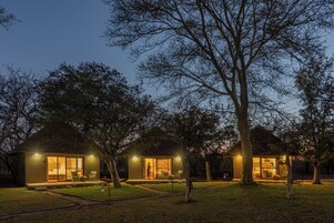 Uma casa moderna de dois andares com grandes janelas de vidro, área de varanda e gramado bem cuidado.