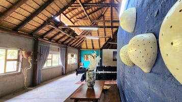 Um quarto rústico com teto de madeira, uma mesa com cadeiras e uma parede decorada com cerâmica.