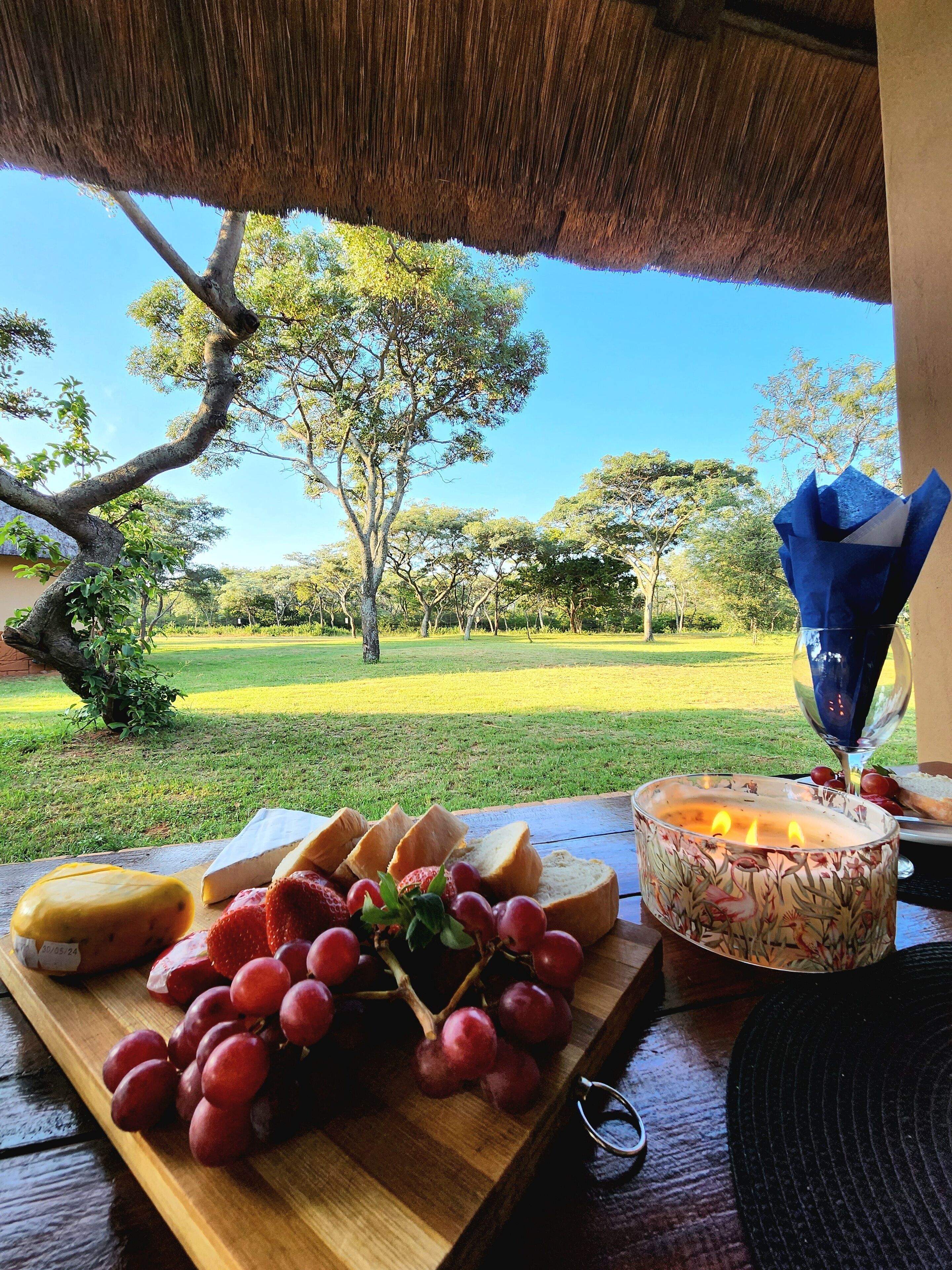 Uma mesa com um prato de frutas, uma vela e um copo de água.