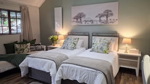Quarto com duas camas, janela com cortinas, um quadro na parede e abajures.