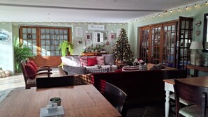 Uma sala de estar acolhedora com um sofá de madeira, uma mesa de jantar e um pinheiro de Natal.