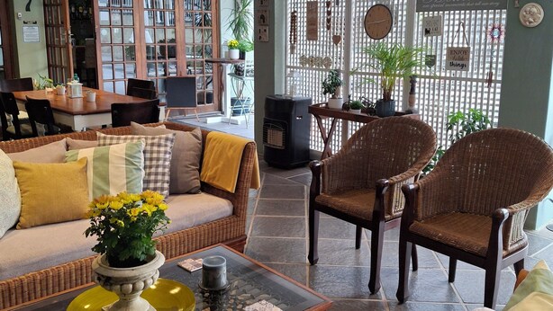 Ampla sala de estar com sofá, cadeiras, mesa de centro e um painel decorativo com placas.