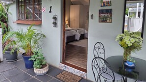 Quarto com cama, uma mesinha e uma cadeira. Há uma janela com vista para o exterior.