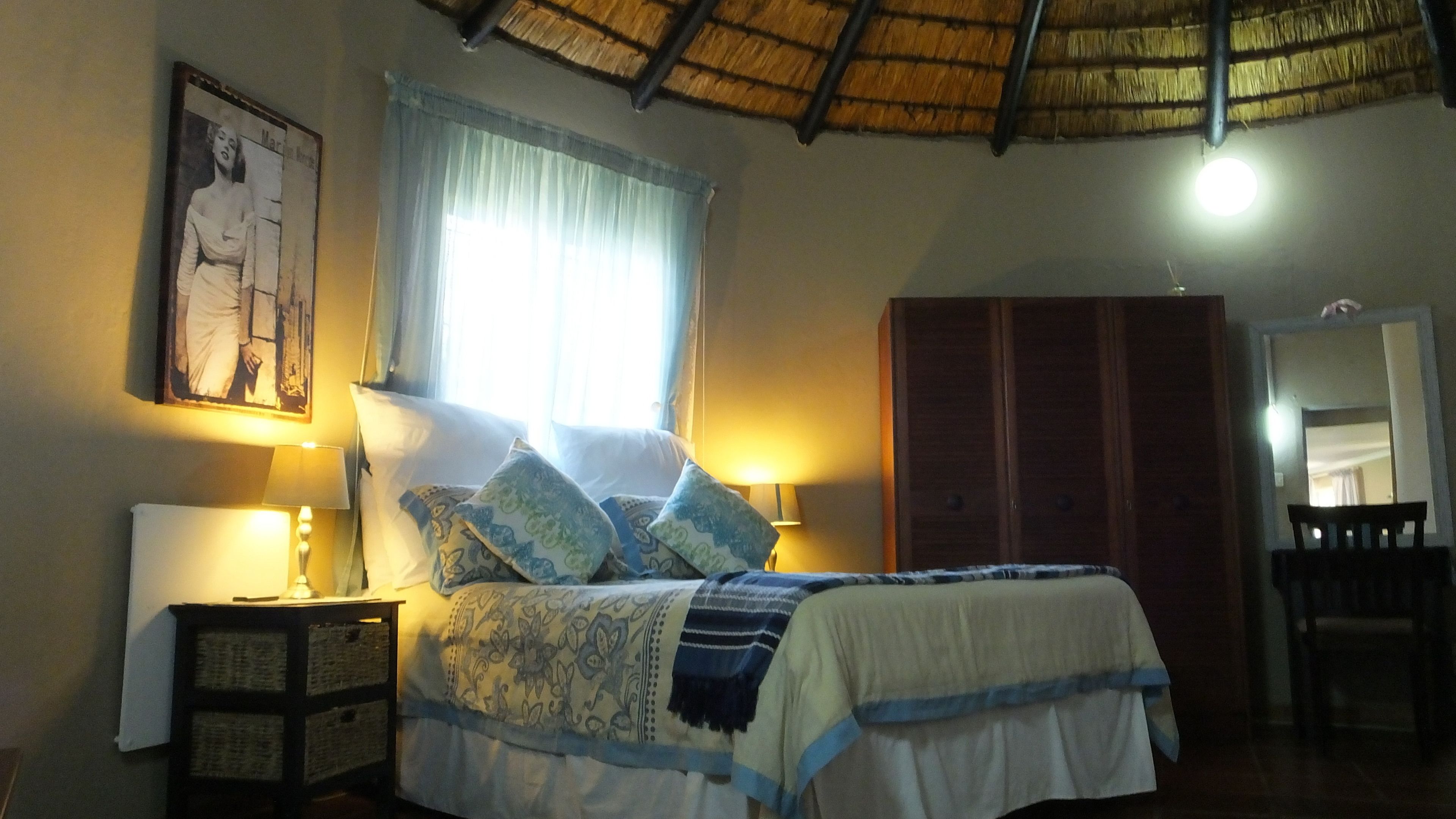 Quarto com cama, mesa de cabeceira, guarda-roupa e espelho.