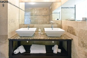 Casa de banho com duas pias, um espelho e um porta-toalhas.