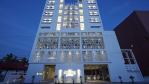 Um hotel moderno com entrada imponente, vários andares e fachada bem iluminada.