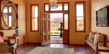 Um quarto com uma porta de madeira grande, um banco, uma mesa e um espelho.