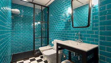 Um banheiro com azulejos de mosaico verde-água, pia branca, vaso sanitário e box de vidro.
