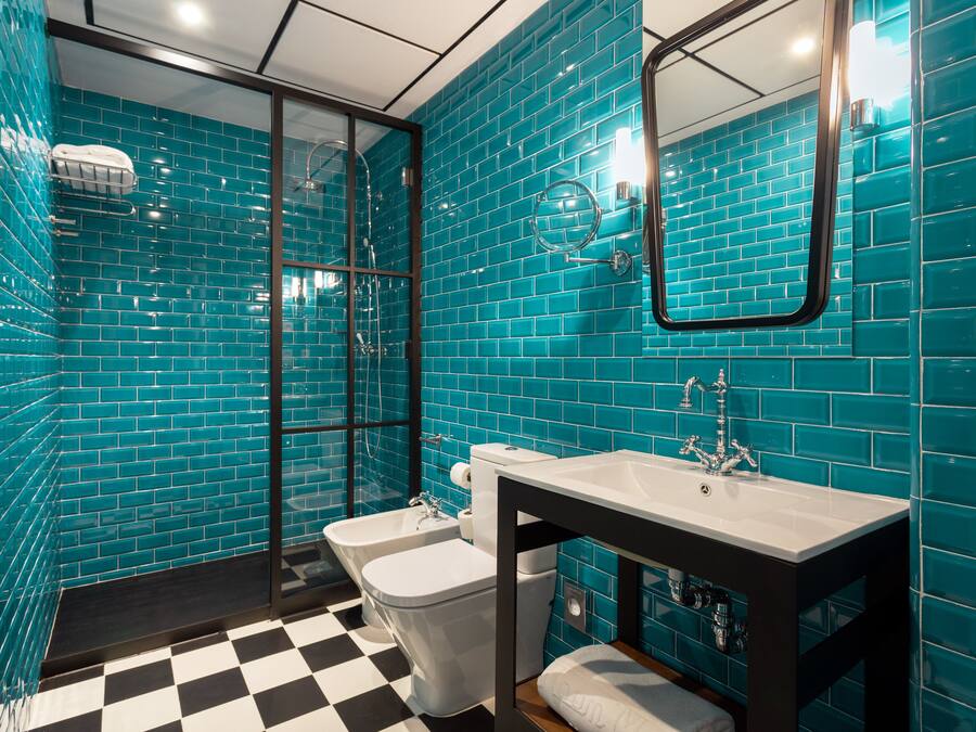 Um banheiro com azulejos de mosaico verde-água, pia branca, vaso sanitário e box de vidro.