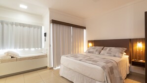 Quarto moderno com cama, mesa de cabeceira e janela com cortinas.