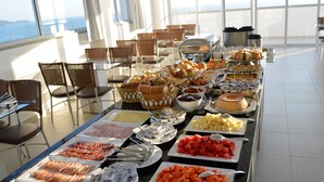 Buffet com diversos alimentos e vista para o oceano.