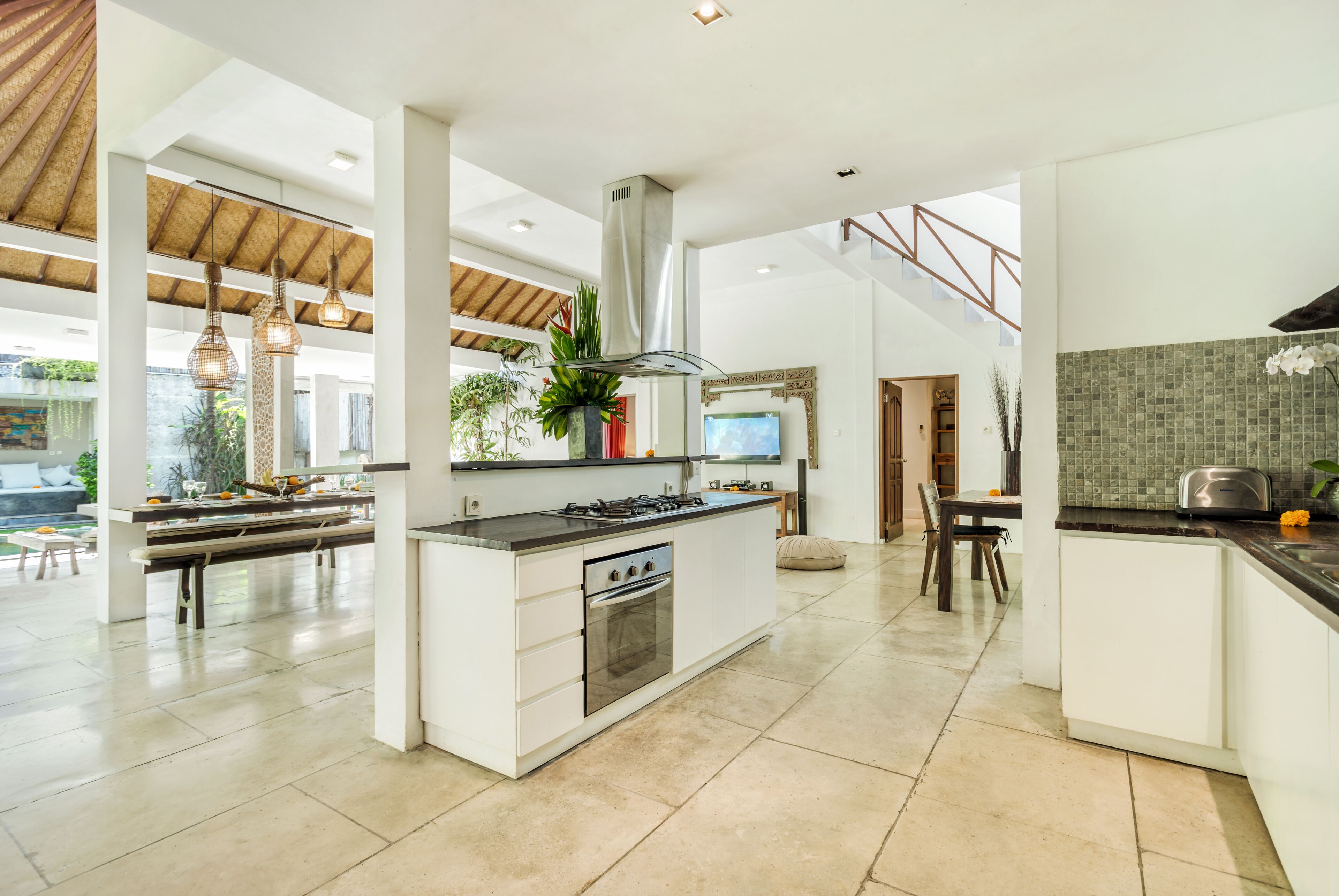 Cozinha espaçosa com ilha central, área de jantar com bancos e escada que leva a um andar superior.