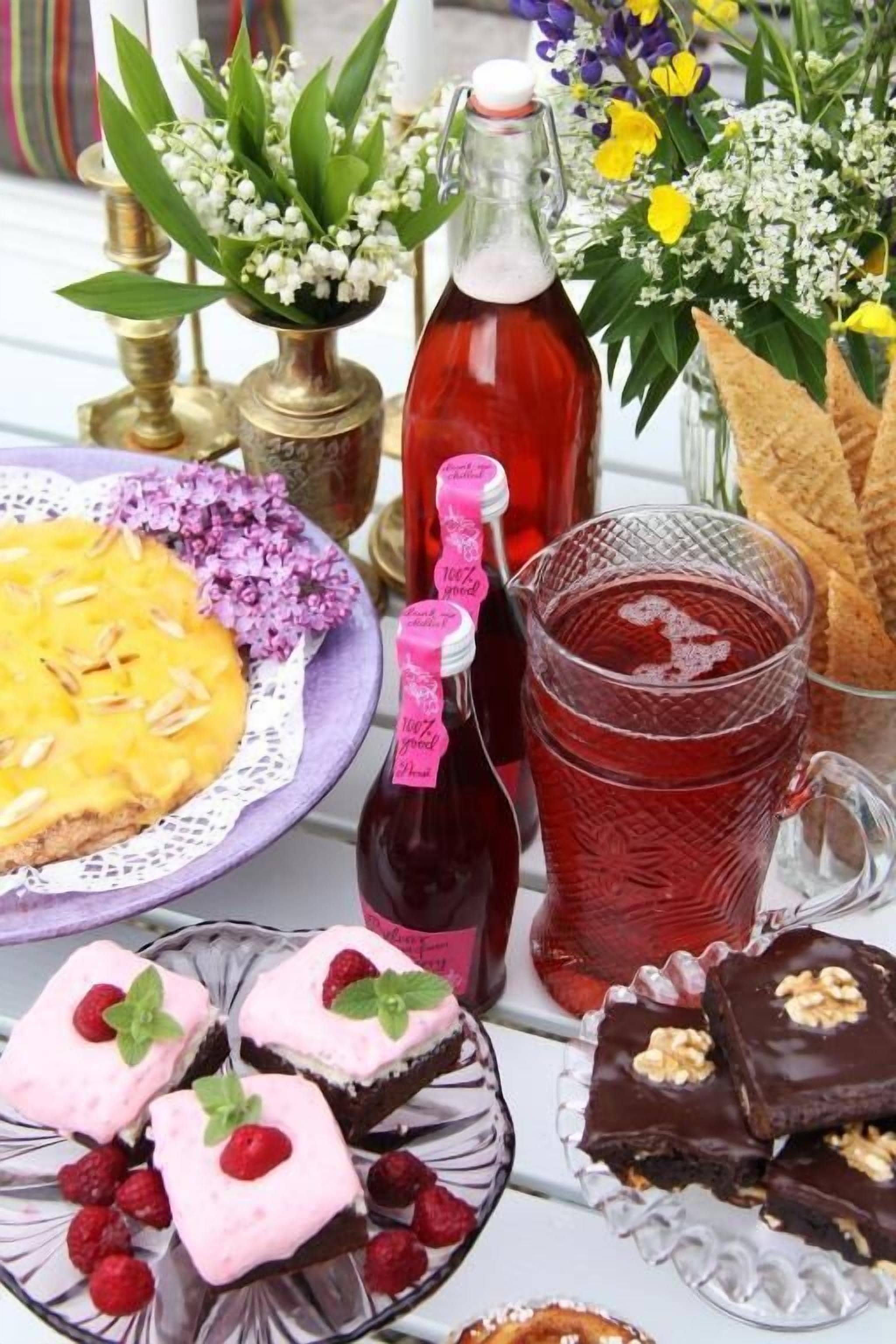 Uma mesa com diversos alimentos, uma garrafa e um copo de bebida vermelha.