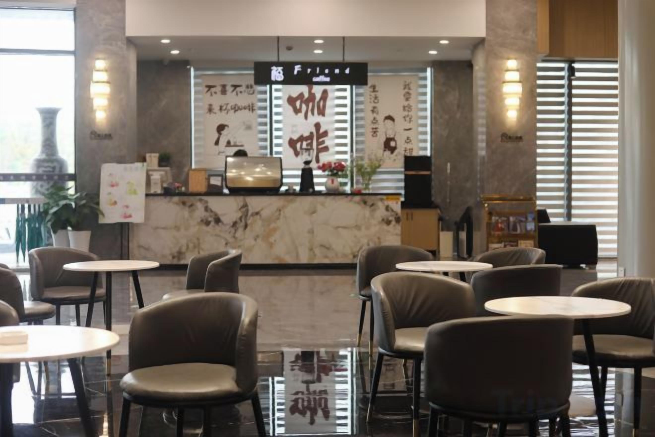 Restaurante com mesas e cadeiras redondas, balcão de mármore e quadro de cardápio.