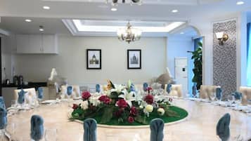 Mesa de jantar redonda com cadeiras, um candelabro e um arranjo de flores.