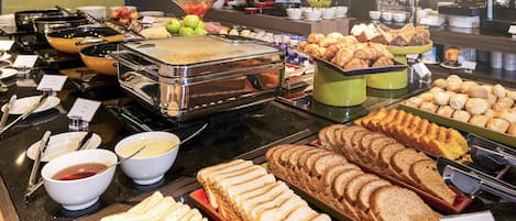 Buffet com diversos alimentos e um chef preparando refeições.