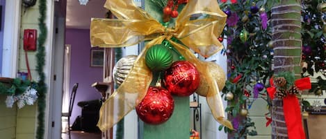 Uma entrada decorada com um grande laço dourado, enfeites vermelhos e verdes e uma coroa de louros.
