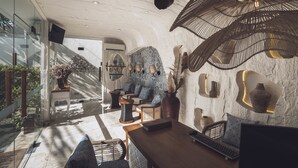 Interior moderno com parede de pedra, luminária de palha no teto e área de estar com tapete estampado.