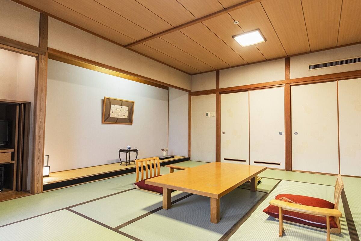 Um quarto em estilo japonês tradicional, com tatames, uma mesa de madeira baixa e portas deslizantes.
