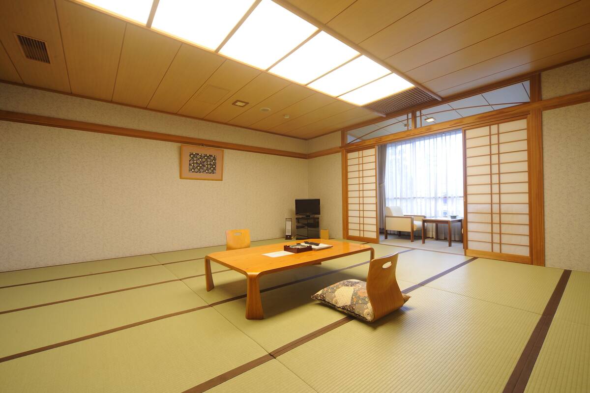 Um quarto japonês tradicional com tatames, uma mesa de madeira baixa, um assento e portas corrediças.