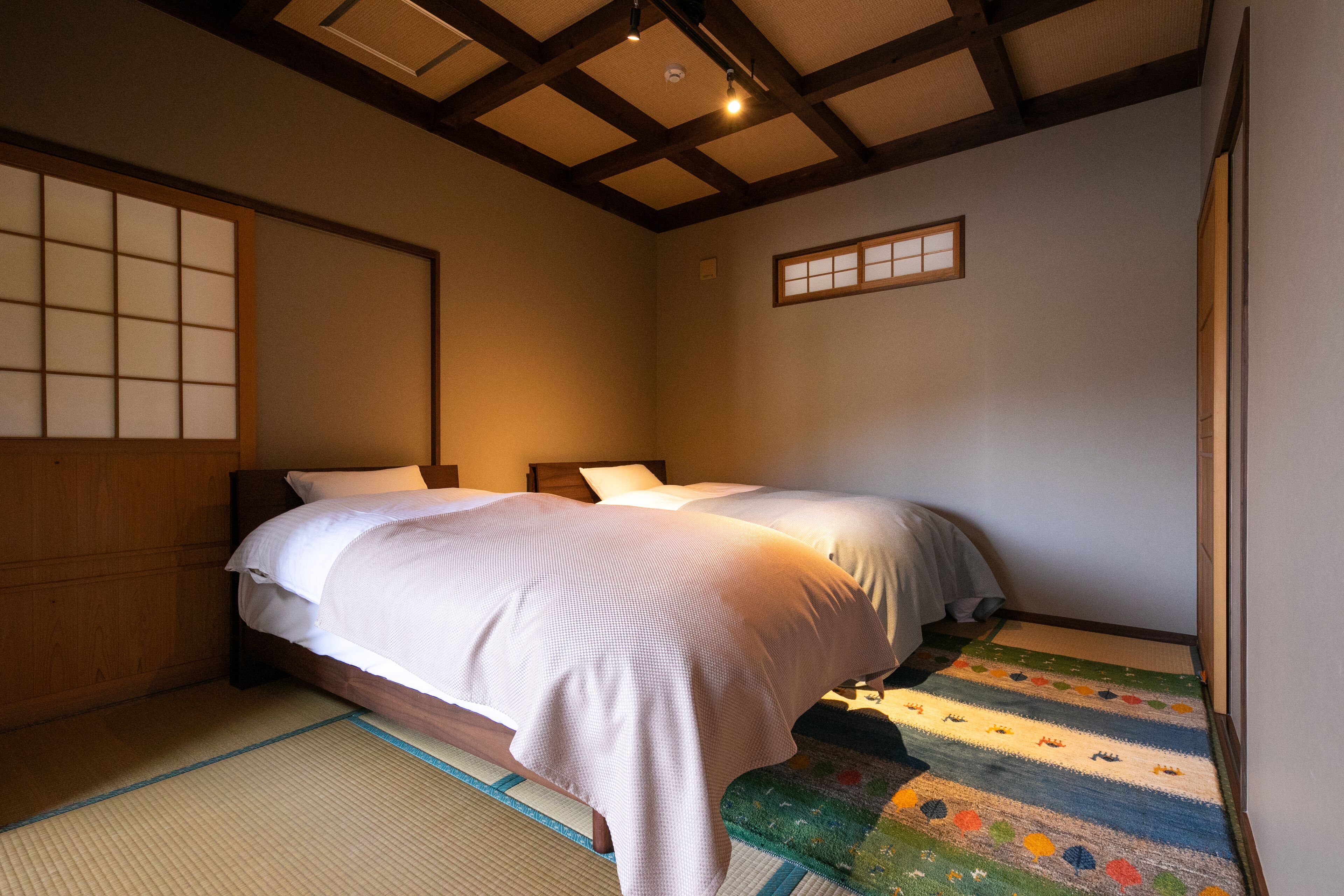 Quarto tradicional japonês, com tatames, cama baixa de madeira e portas shoji.