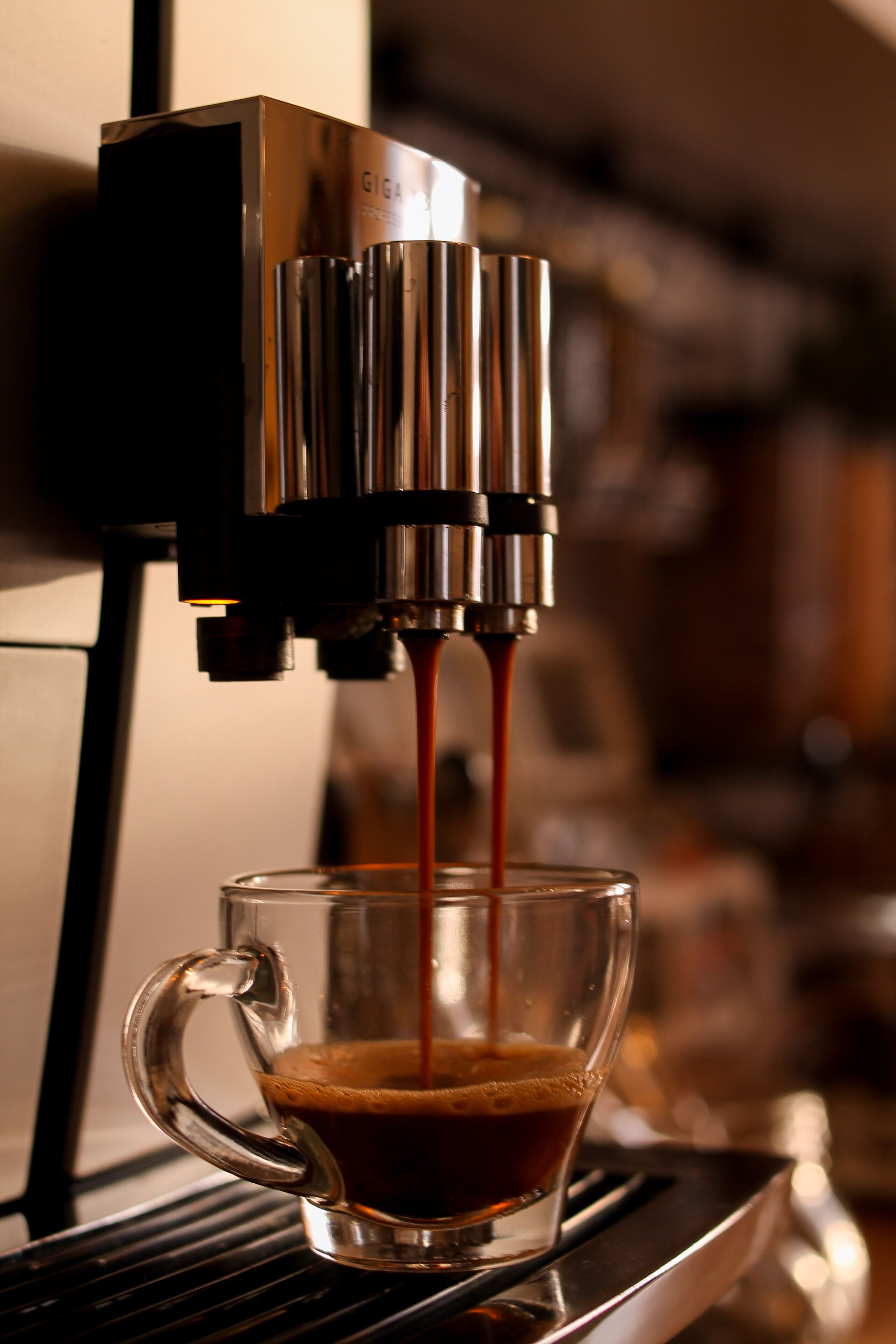Máquina de café servindo café em uma xícara de vidro.