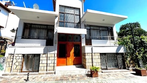 Um edifício de dois andares com entrada central, varandas e fachada térrea em azulejos.