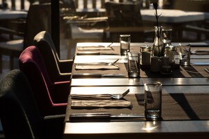 Uma mesa de restaurante posta com talheres, copos e temperos.