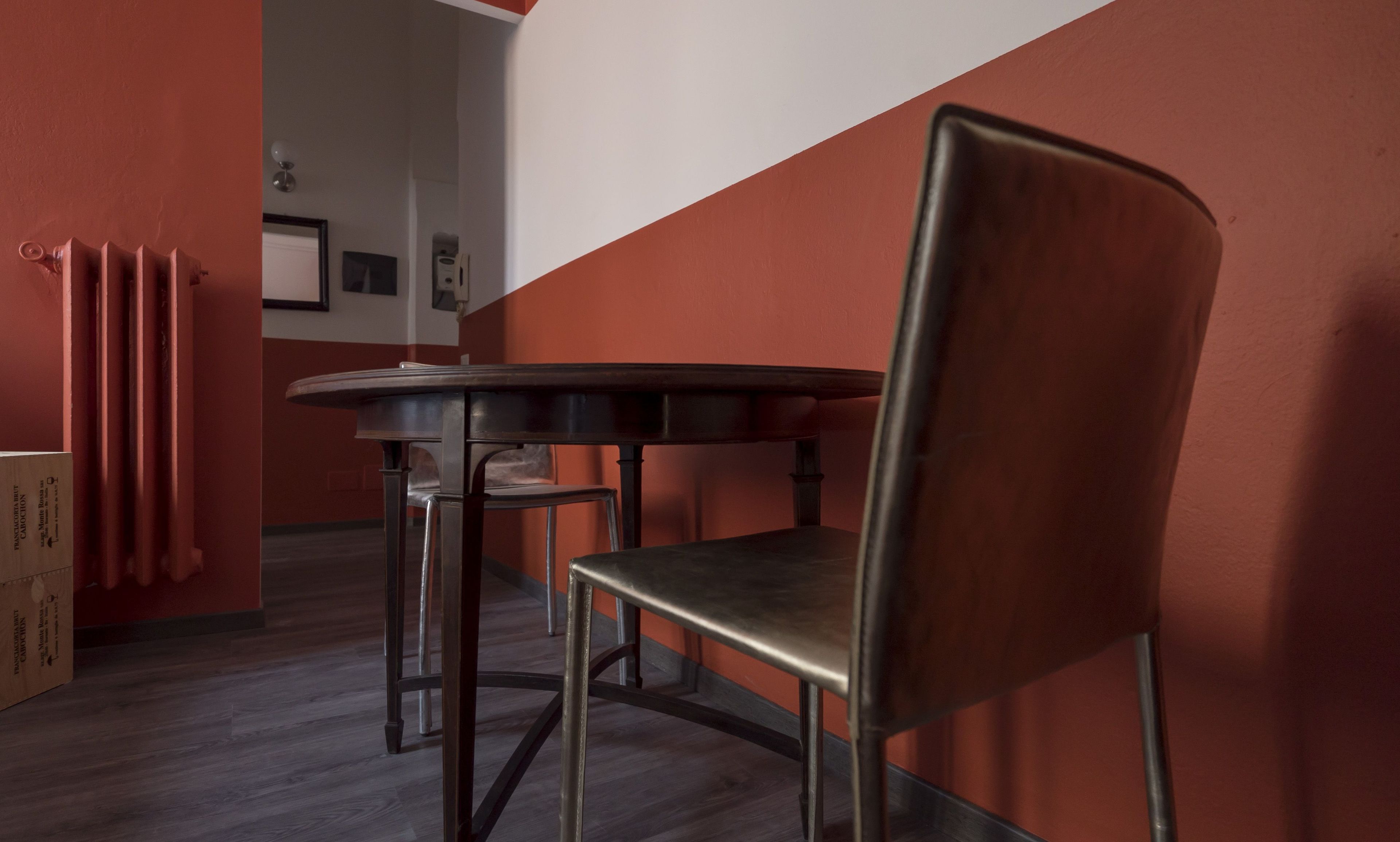 Uma área de refeições com uma mesa redonda e uma cadeira, um radiador e um quadro na parede.