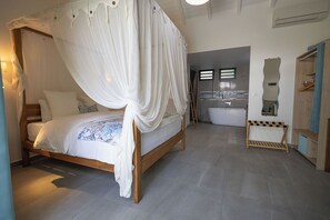Quarto com cama de dossel, guarda-roupa de madeira e banheiro com banheira.