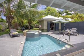 Piscina com espreguiçadeiras, ofurô e área de varanda coberta.