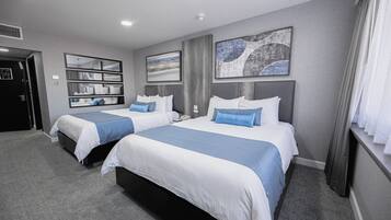 Quarto de hotel com duas camas, um espelho grande e obras de arte nas paredes.