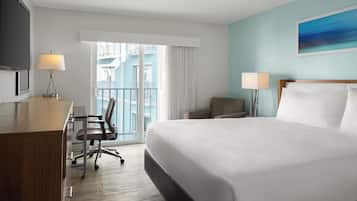Quarto de hotel com cama, escrivaninha, cadeira e duas luminárias.