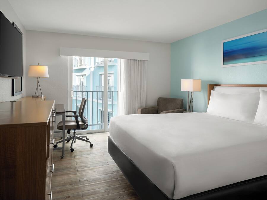 Quarto de hotel com cama, escrivaninha, cadeira e duas luminárias.