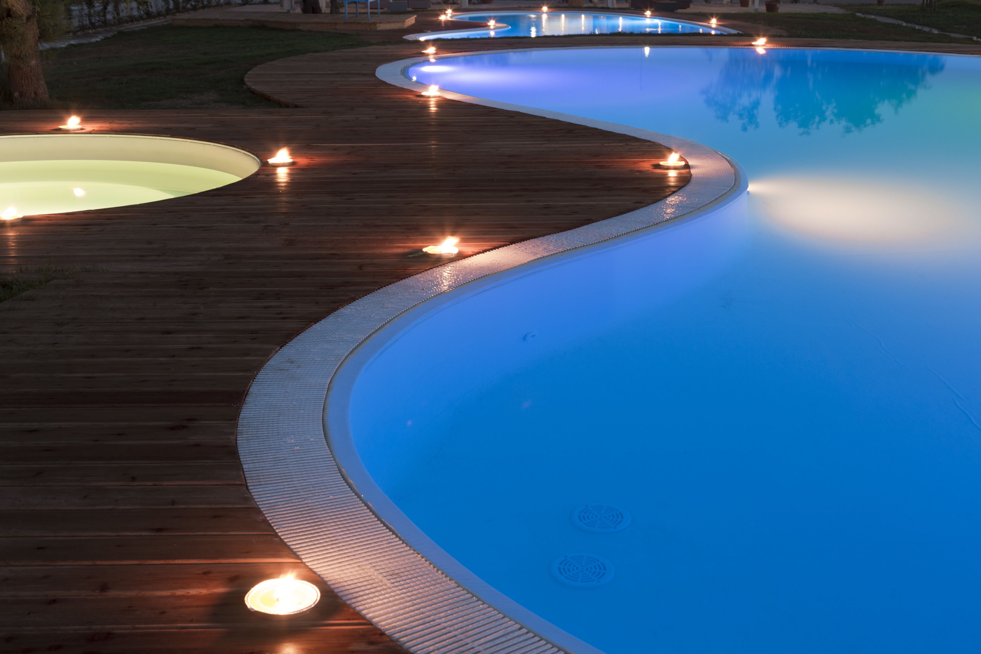 Piscina com deck de madeira e borda curva.