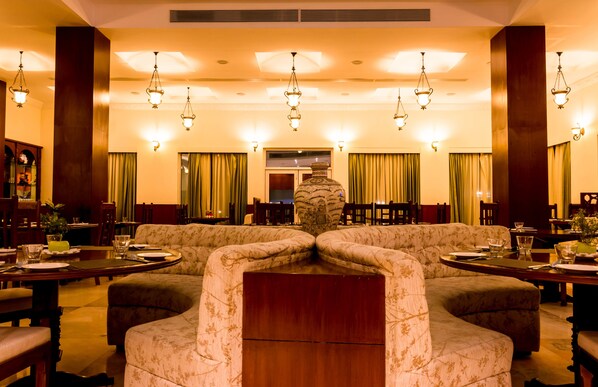 Uma sala de jantar com uma mesa redonda central, rodeada por sofás e cadeiras.