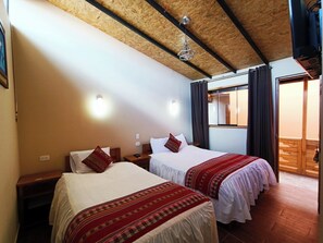Quarto com duas camas, vigas de madeira no teto, luminária pendente e janela com cortinas.