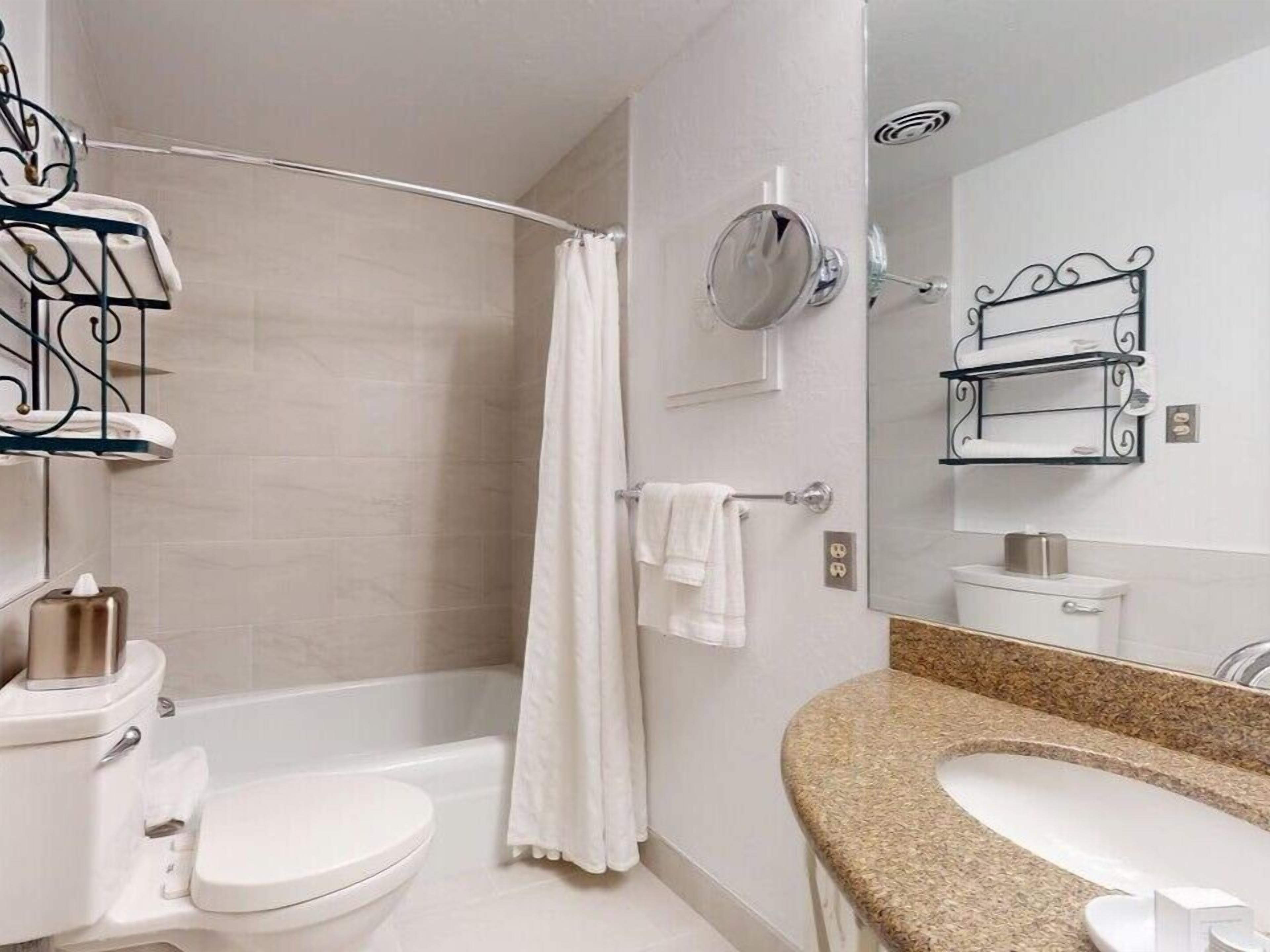 Uma casa de banho moderna com chuveiro, sanita e lavatório.