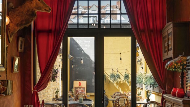 Restaurante com cortinas vermelhas, móveis de madeira e uma decoração com cabeça de veado.