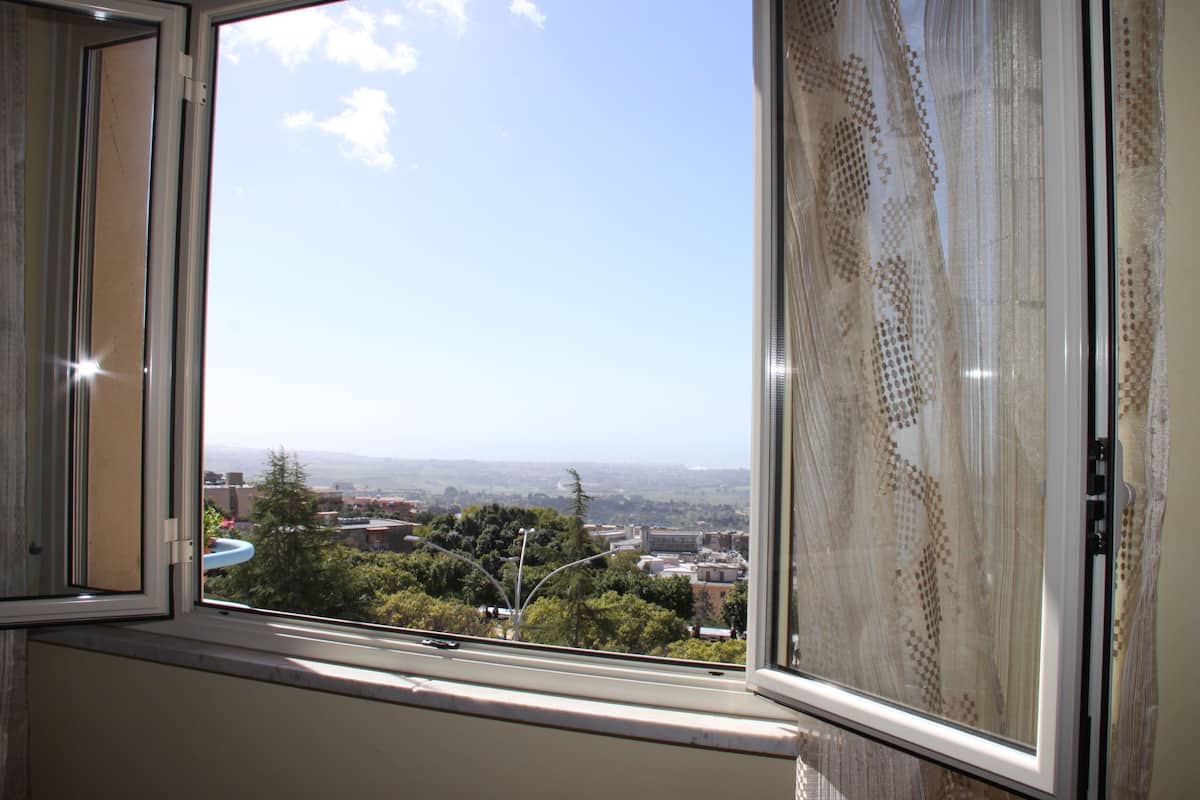 Uma janela com vista para um horizonte urbano, incluindo edifícios e áreas verdes.