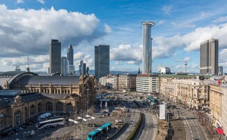 Paisagem urbana com edifícios históricos, uma torre moderna e uma linha de bonde.
