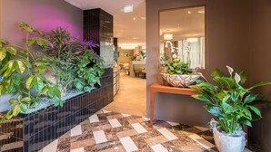Um hall de hotel moderno com piso xadrez, balcão de recepção e um espelho grande.