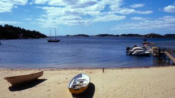 Uma praia com dois barcos, um cais e mar calmo.
